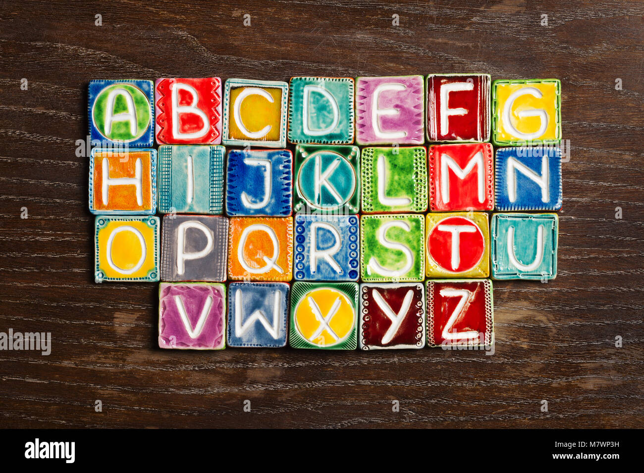 Colorful handmade ceramic alphabet on wood texture Stock Photo - Alamy