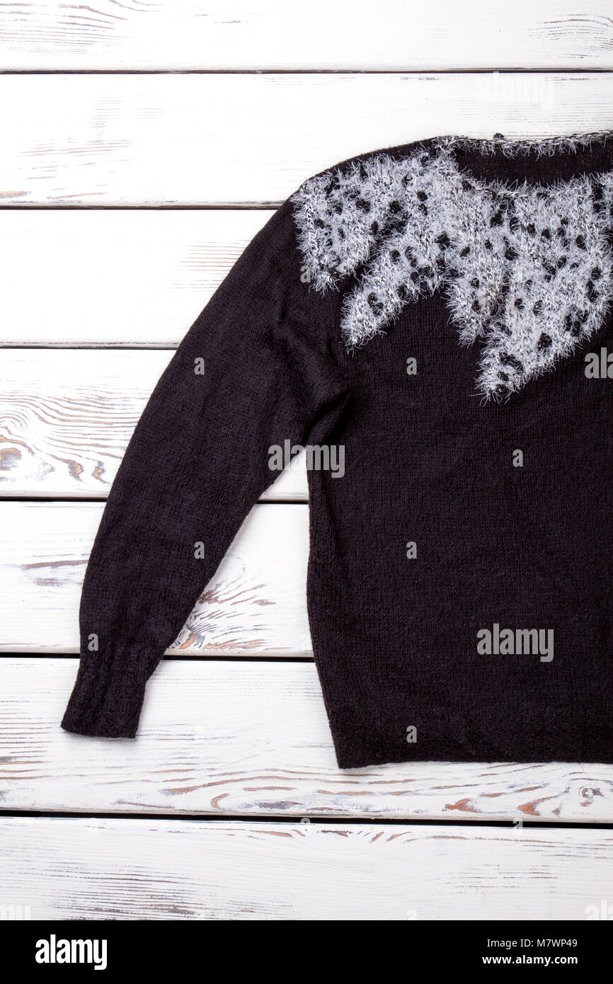 Black sweater sleeve. Cropped view pullover. White wooden desk ...