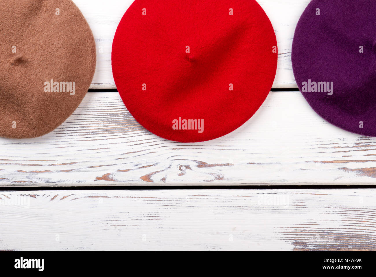 Red colourful berets top view. Flat lay. White wooden background Stock ...