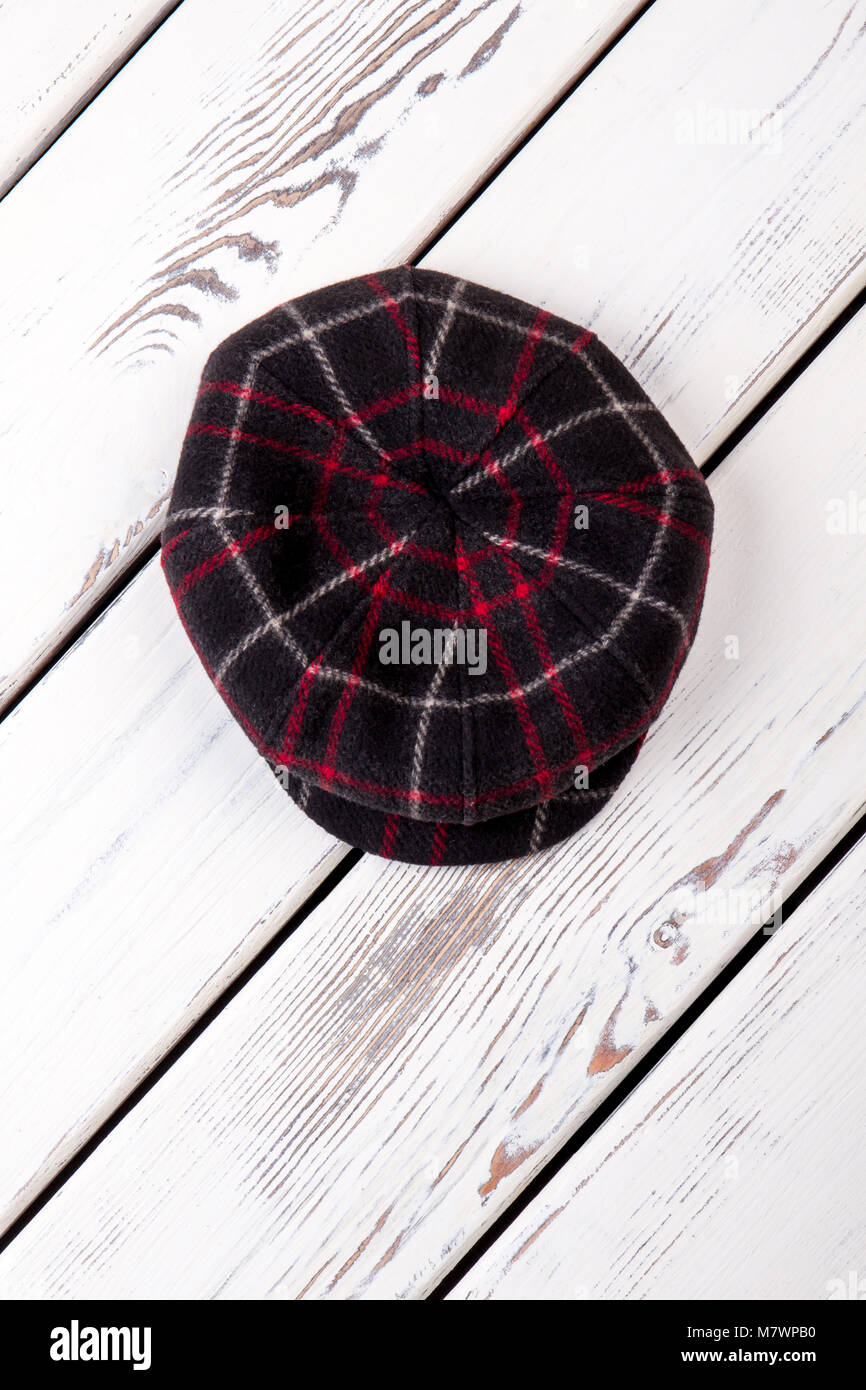 Checkered women's cap. Flat lay, top view. White wooden background ...