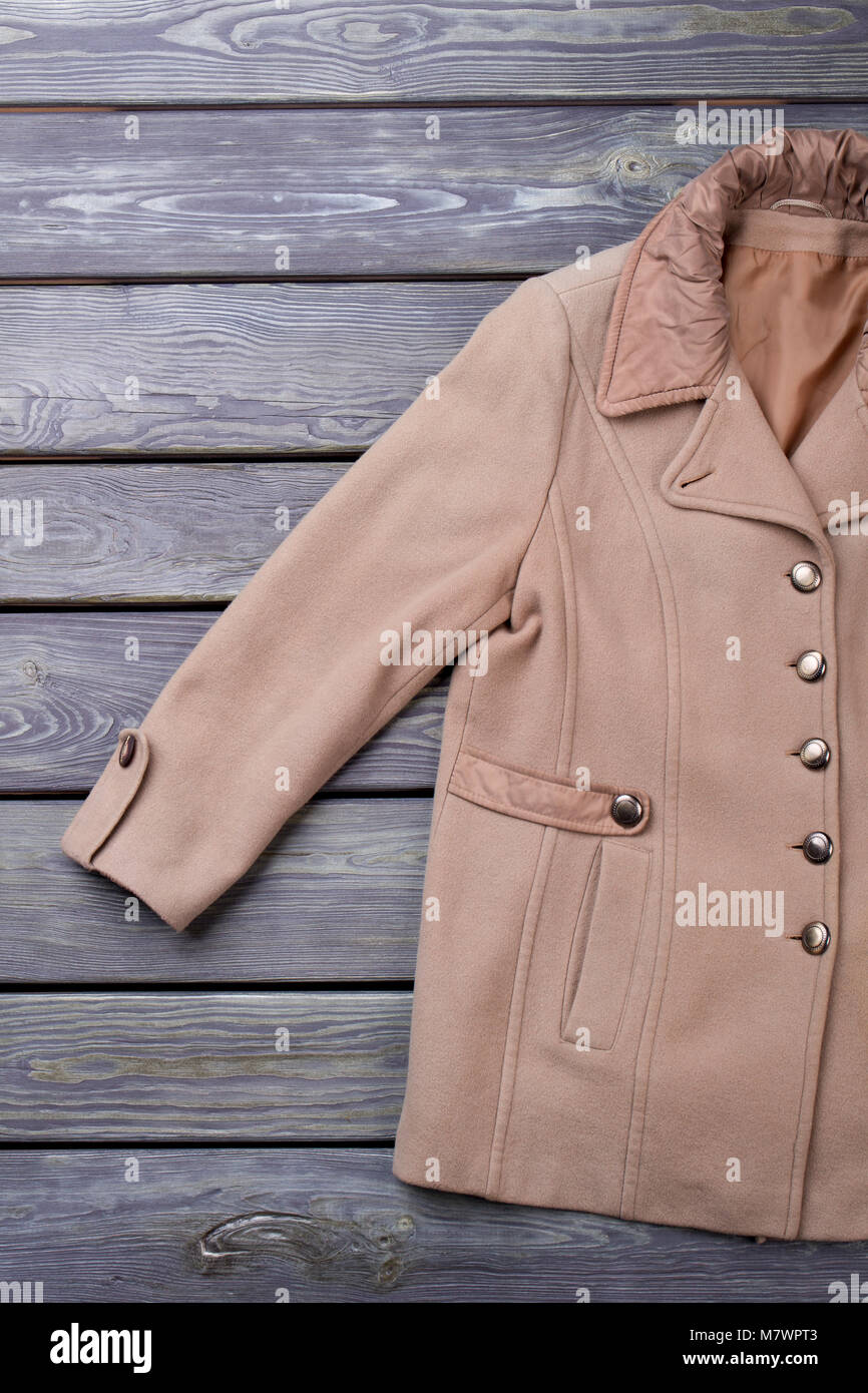 Beige winter jacket. Vertical cropped image. Grey wooden surface ...
