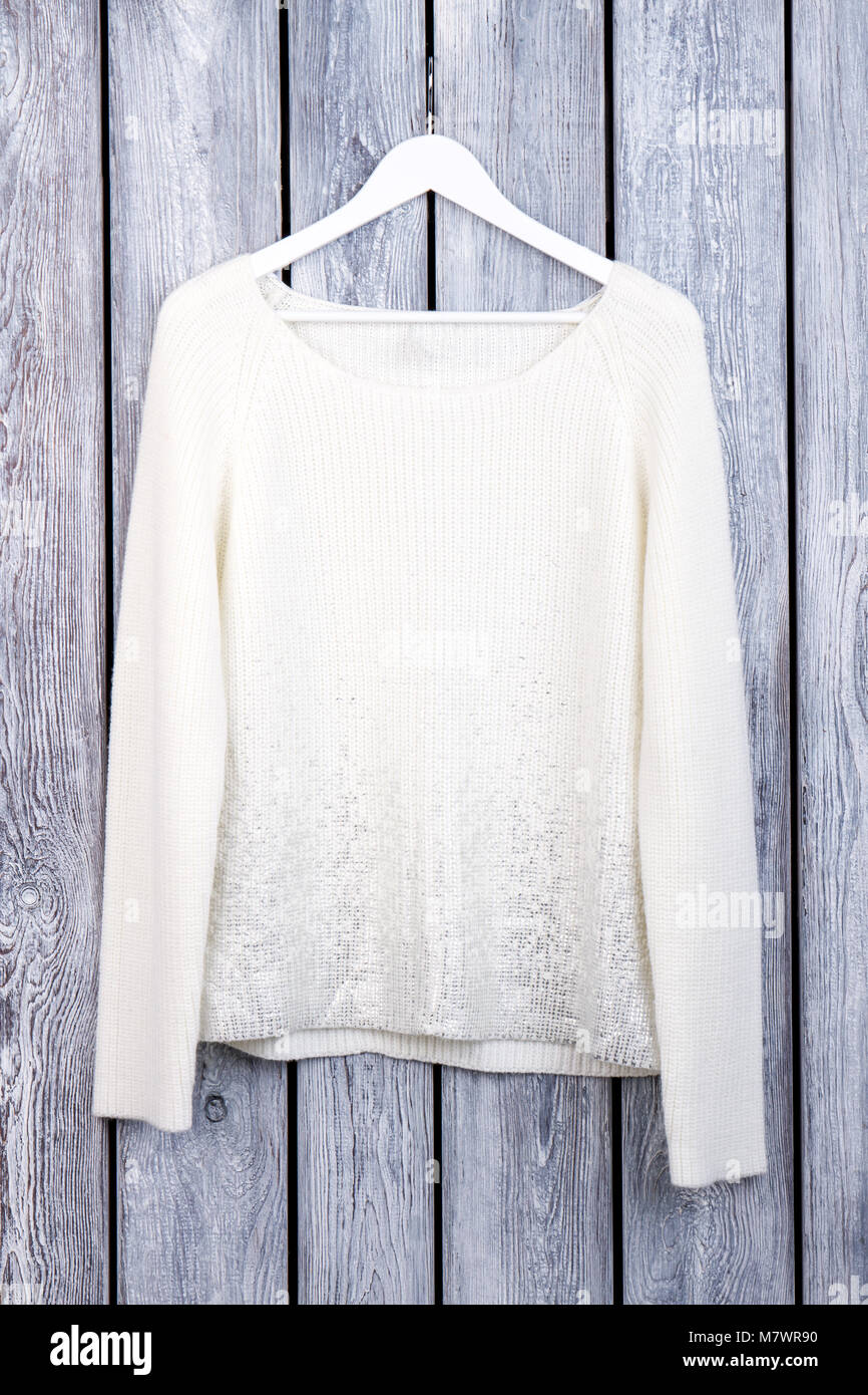 White wool sweater on hanger. Grey wooden desk surface background Stock ...
