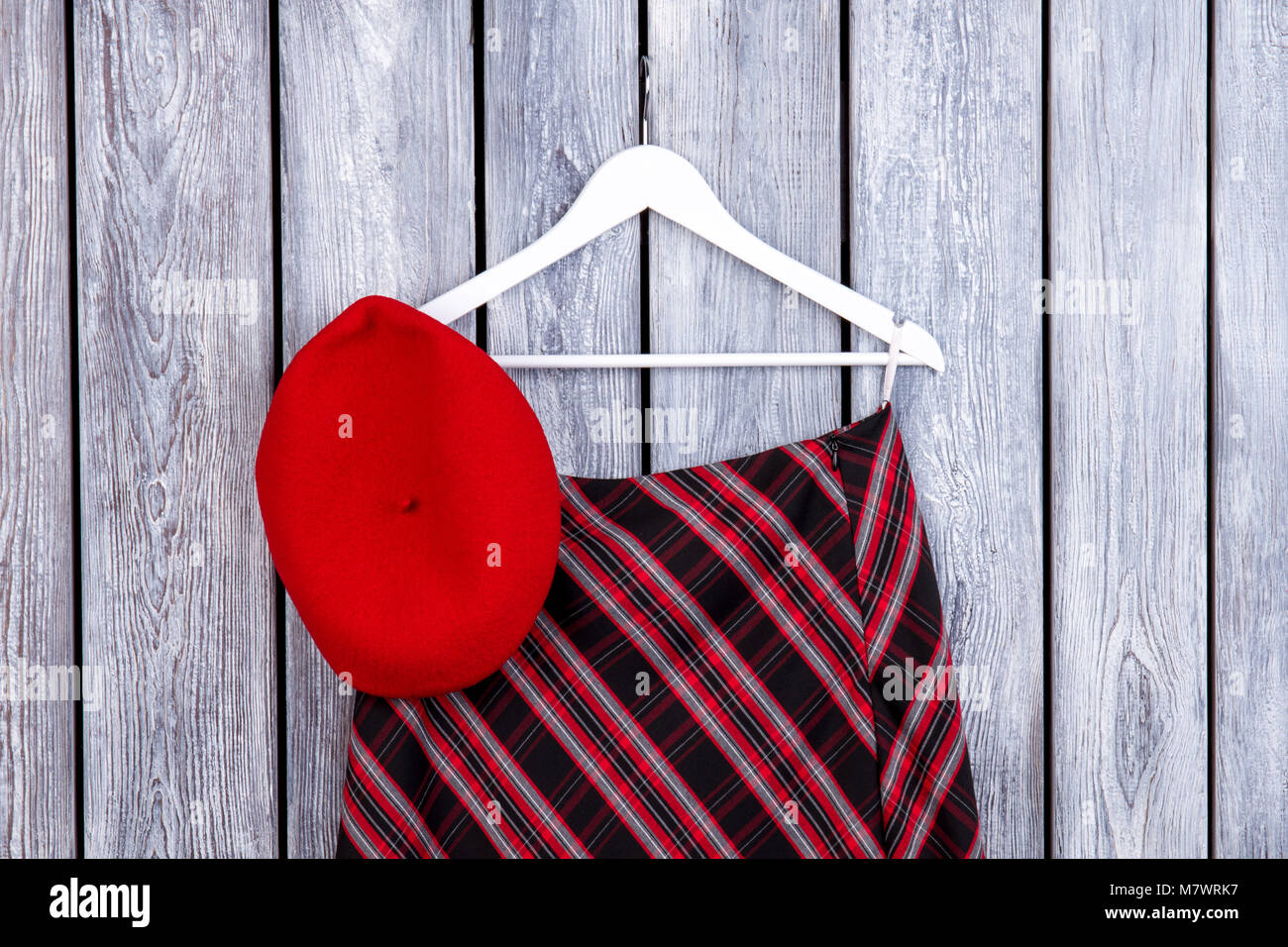 Top view beret hat and checkered skirt on hanger. Desk surface ...