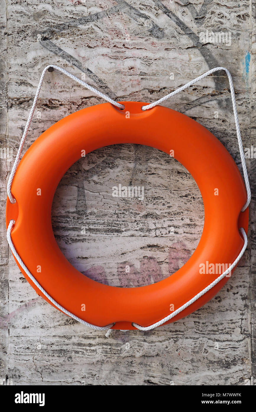 Orange Plastic Life Ring Saver at Wall Stock Photo - Alamy