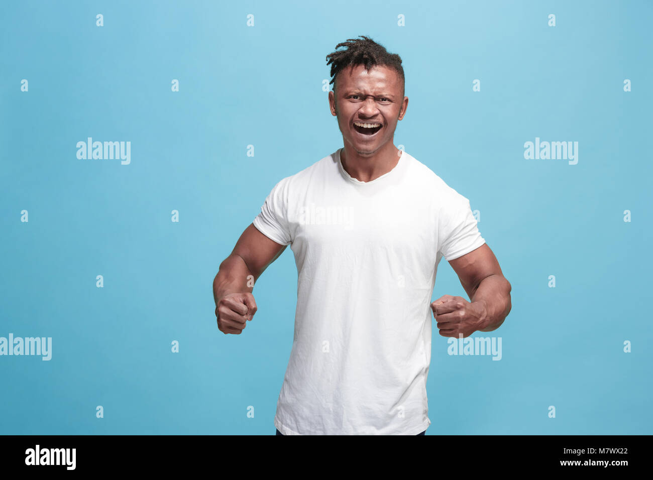 The young emotional angry afro man screaming on blue studio background ...