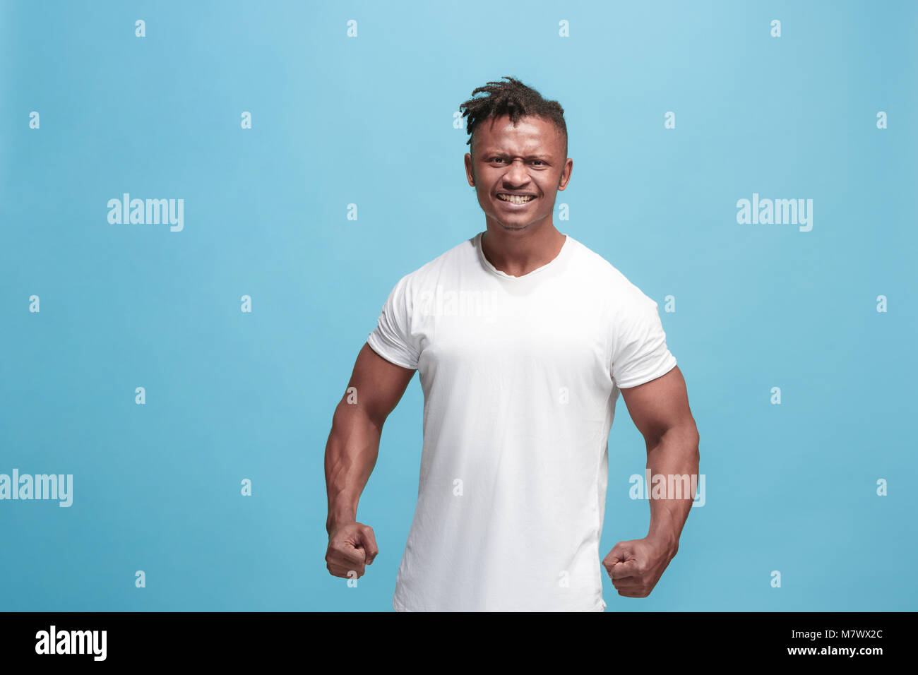 The young emotional angry afro man screaming on blue studio background ...