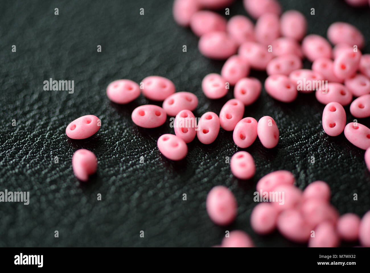 Scattered twin beads pink color on a dark surface close up Stock Photo ...