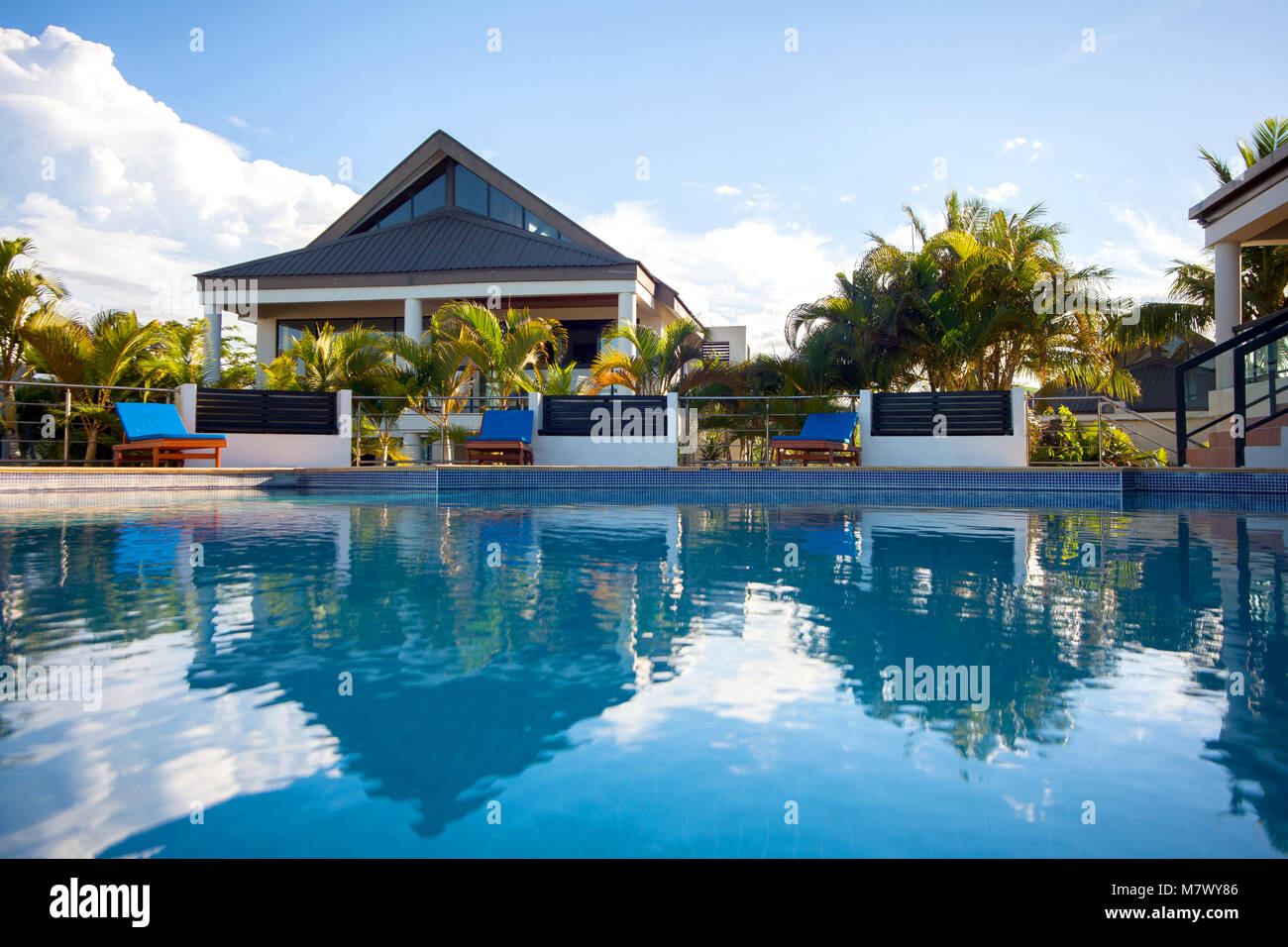 View of luxury villas with swimming pool and seats surrounded by palms ...