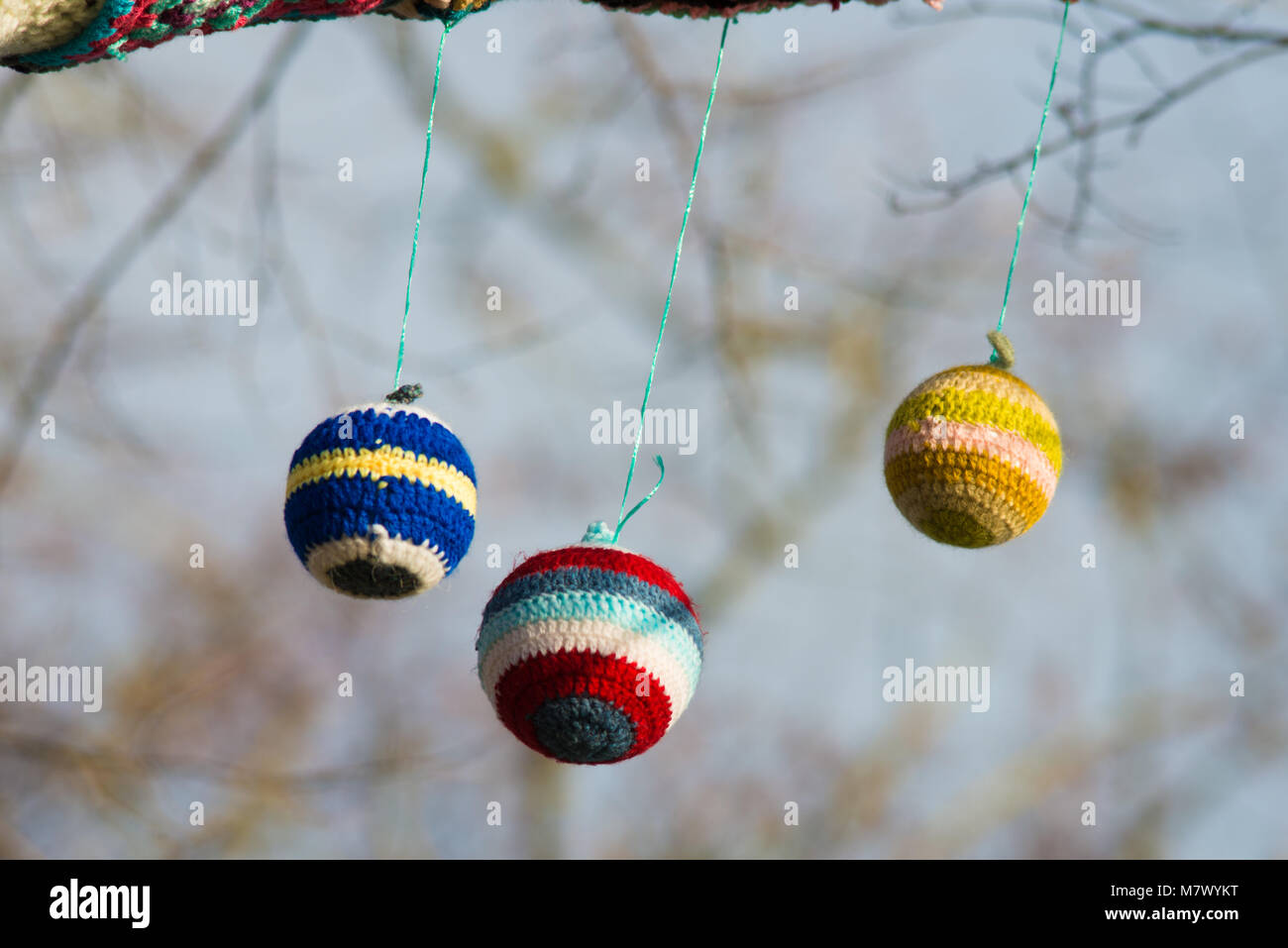 yarn bomb tree with baubles in the winter with blue sky background ...