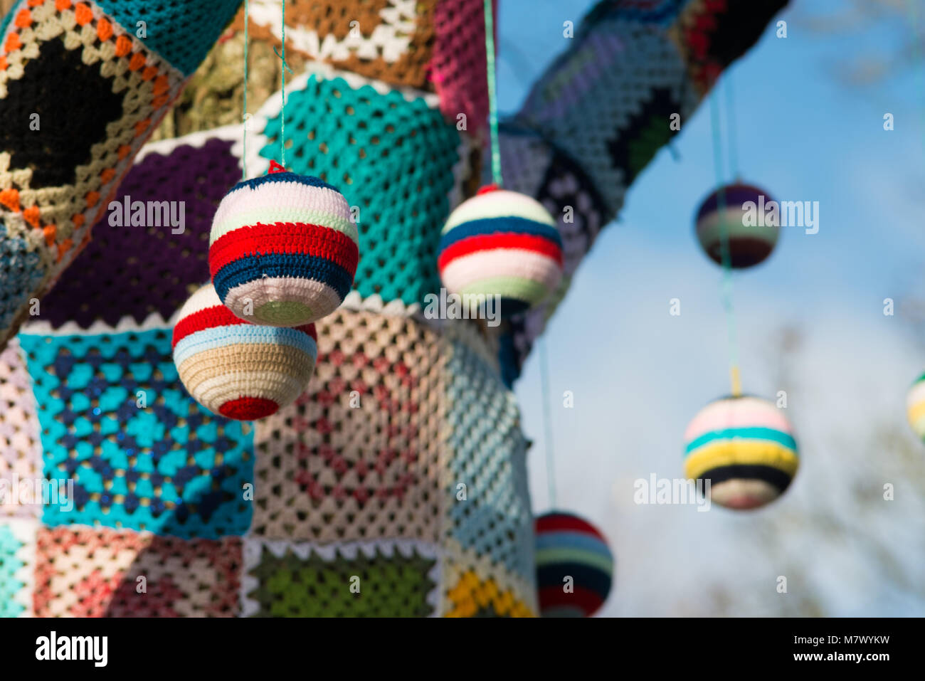 yarn bomb tree with baubles in the winter with blue sky background ...