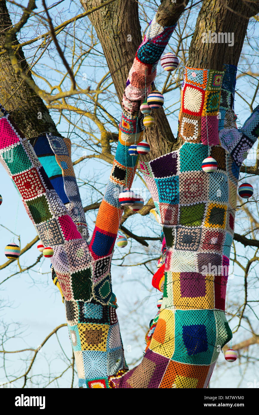 yarn bomb tree with baubles in the winter with blue sky background ...