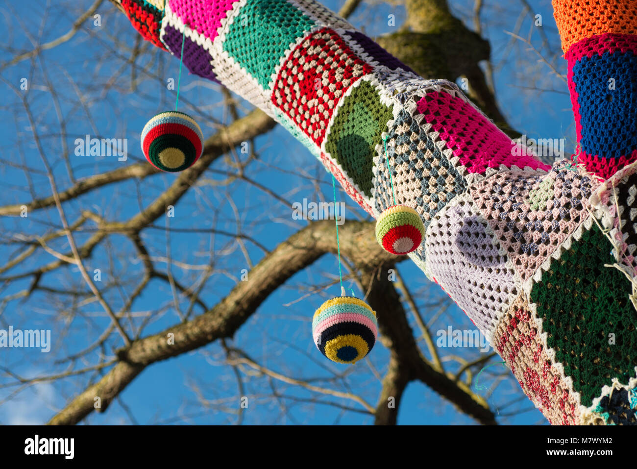 yarn bomb tree with baubles in the winter with blue sky background ...