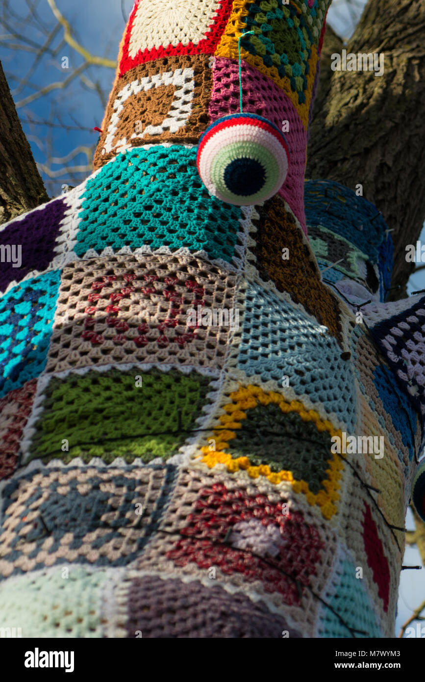 yarn bomb tree with baubles in the winter with blue sky background ...