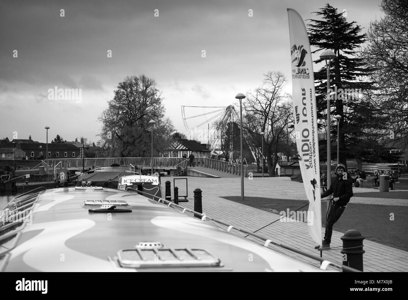 black and white man pulling on rope to moor canal barge with quarter ...