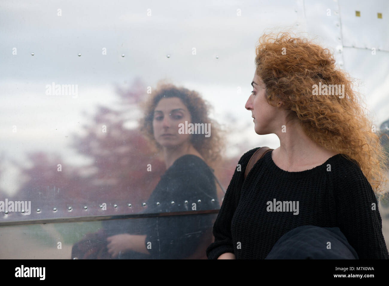 woman taking a passing look at reflection in side of American style ...