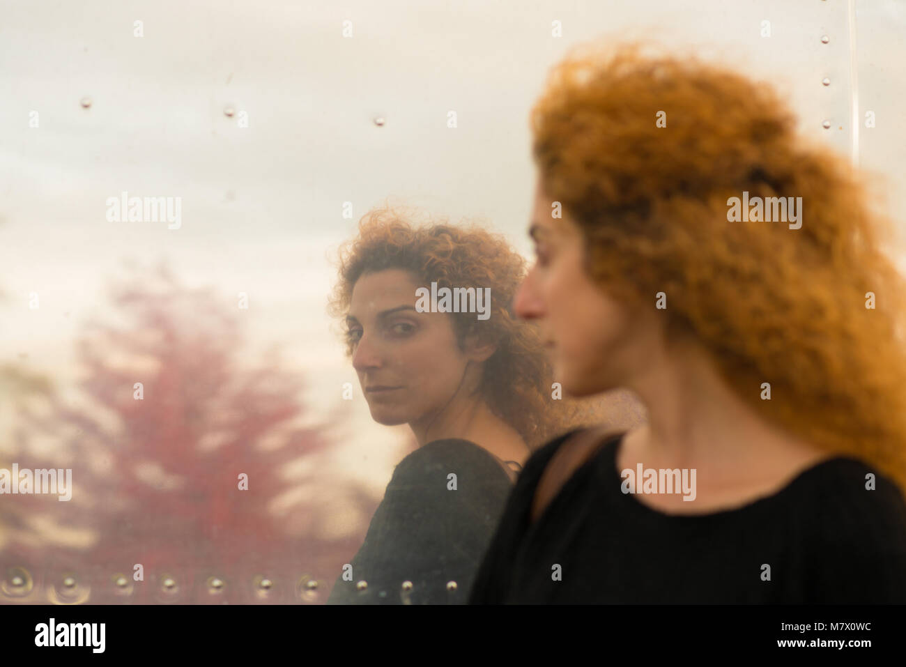 woman taking a passing look at reflection in side of American style ...