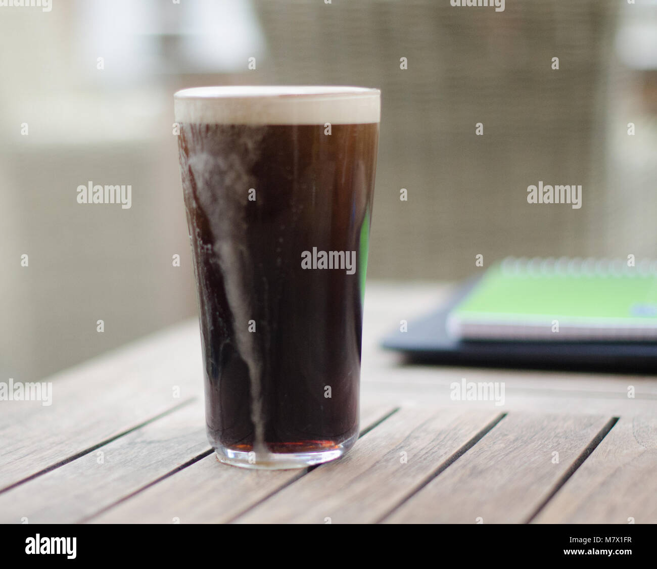 pint of black stout beer on pub table with school work excercise books ...