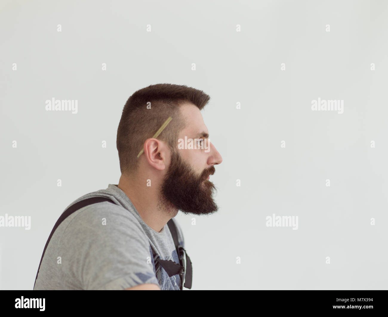 portrait of bearded hipster handyman with pen behind ear isolated on ...