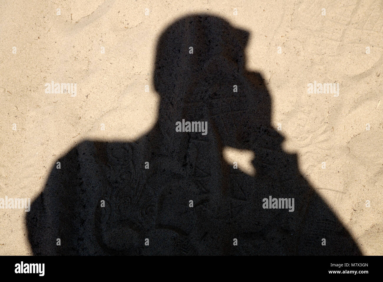 Shadow of man traveler with backpack take photo on sand beach at sunset ...