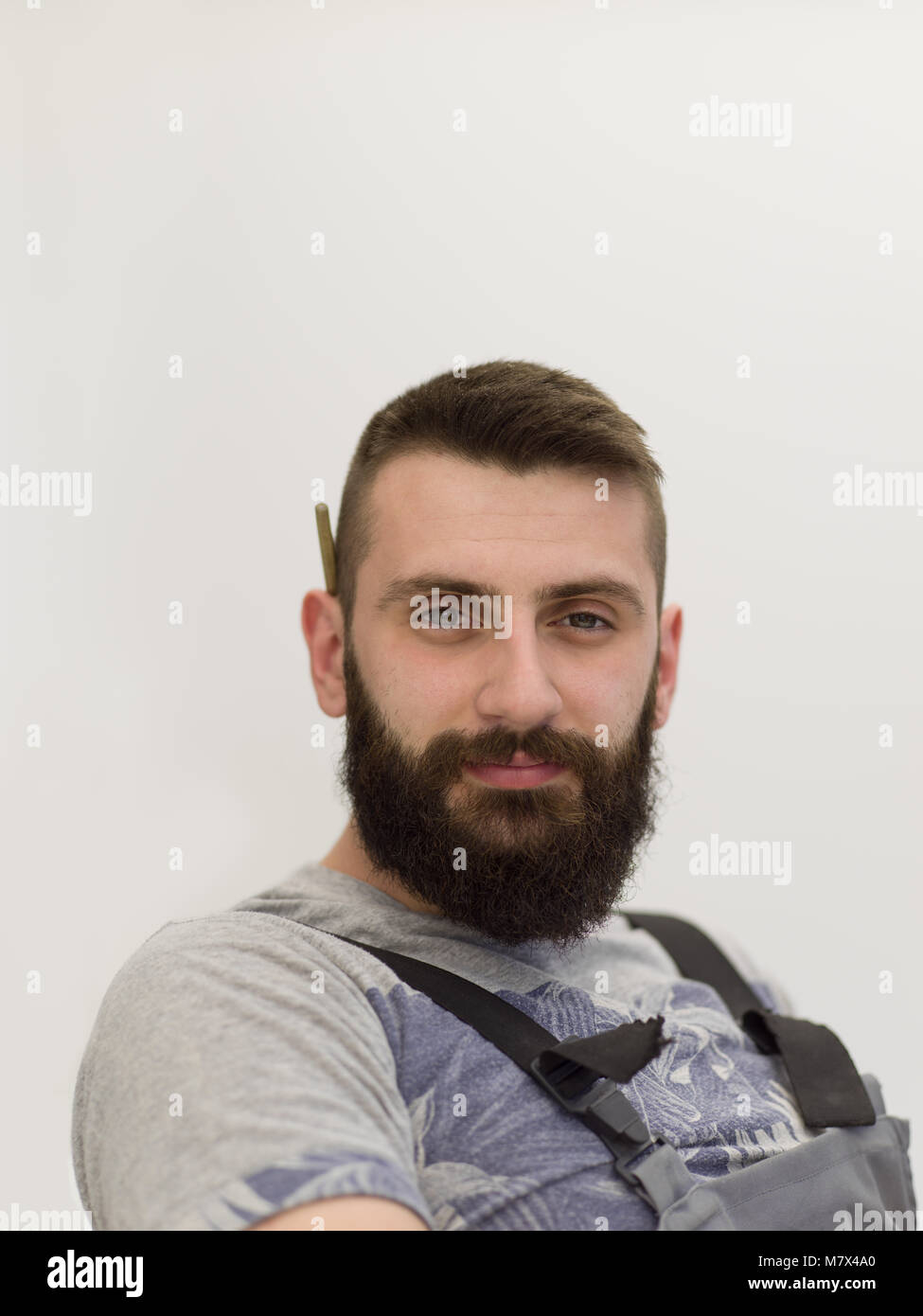 portrait of bearded hipster handyman with pen behind ear isolated on ...