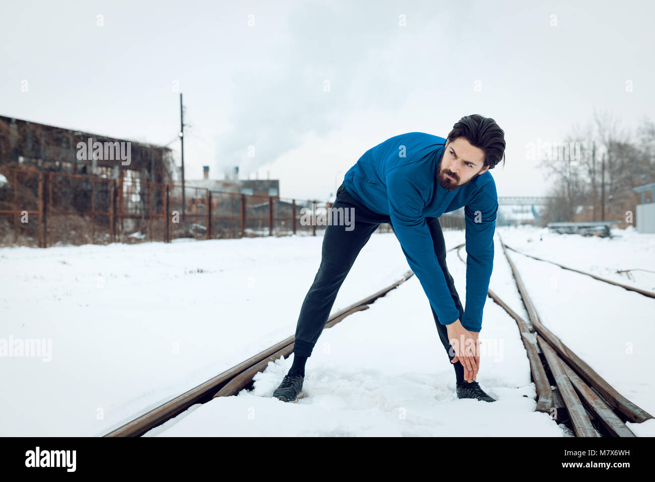 Active young man stretching and doing exercises in the public place ...