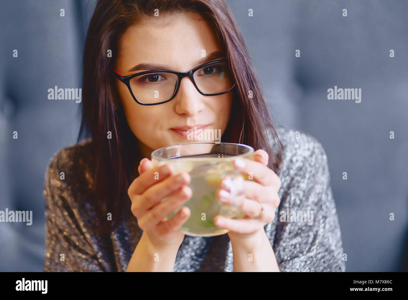 portrait of a young pretty girl drinking hot tea with lemon in a cafe ...