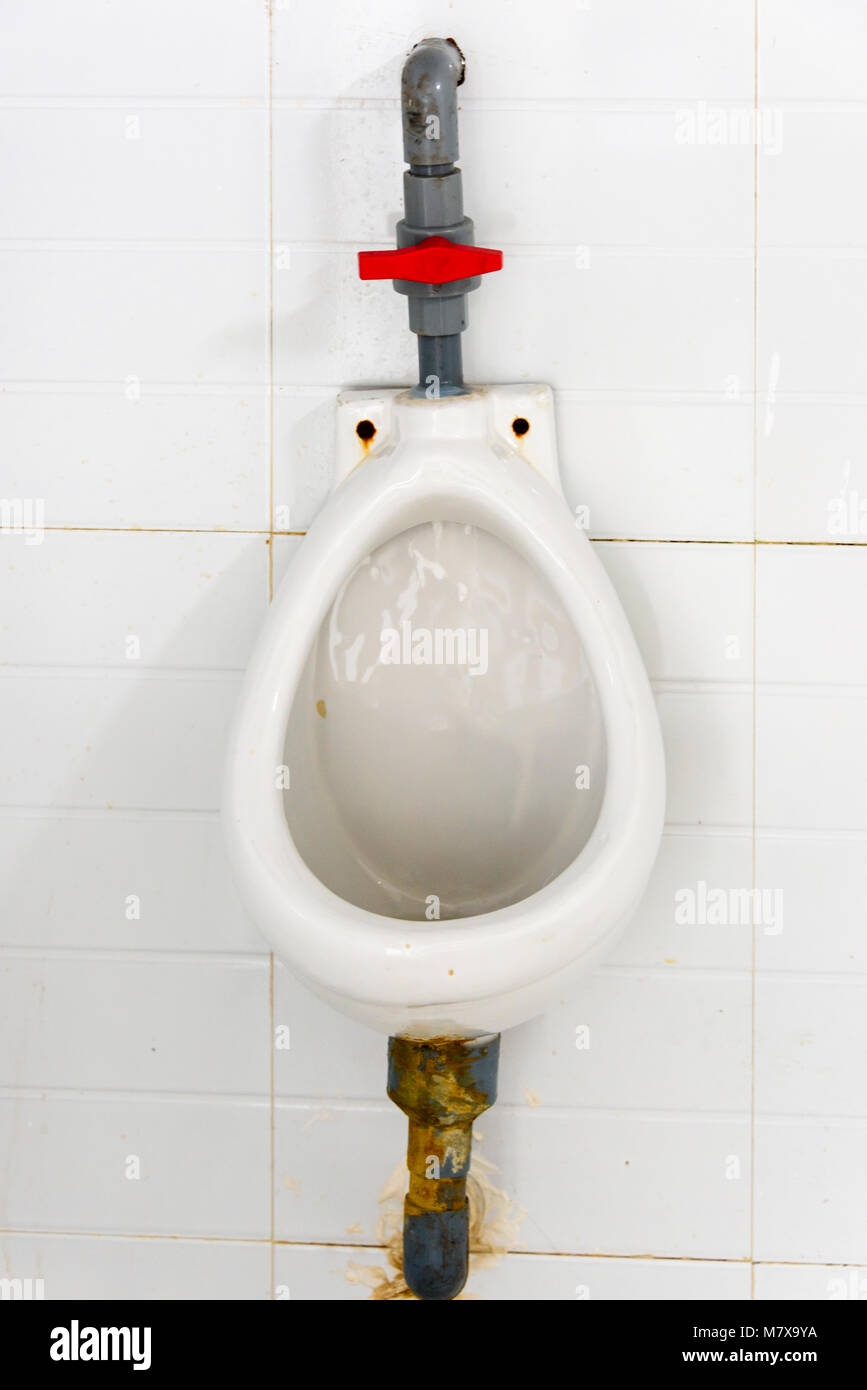 Dirty urinal with a manual valve to flush it Stock Photo - Alamy