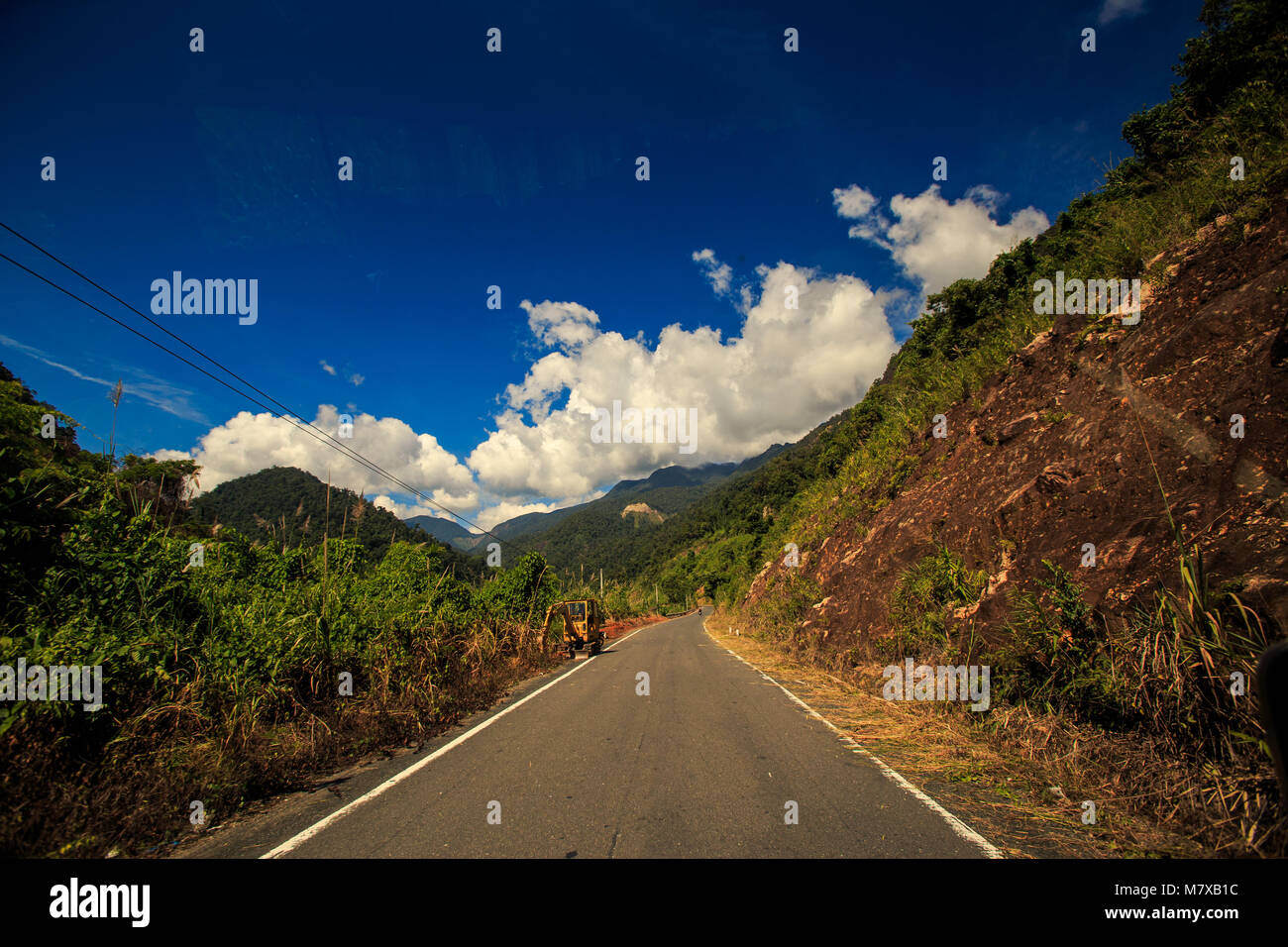 view of sunny highway among hills against blue sky out of car window ...