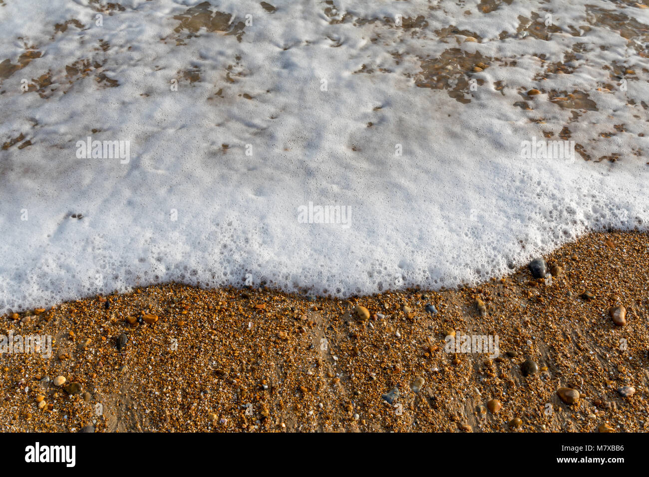 Fine shingle and sand with surf in the top half of the frame on a sunny ...