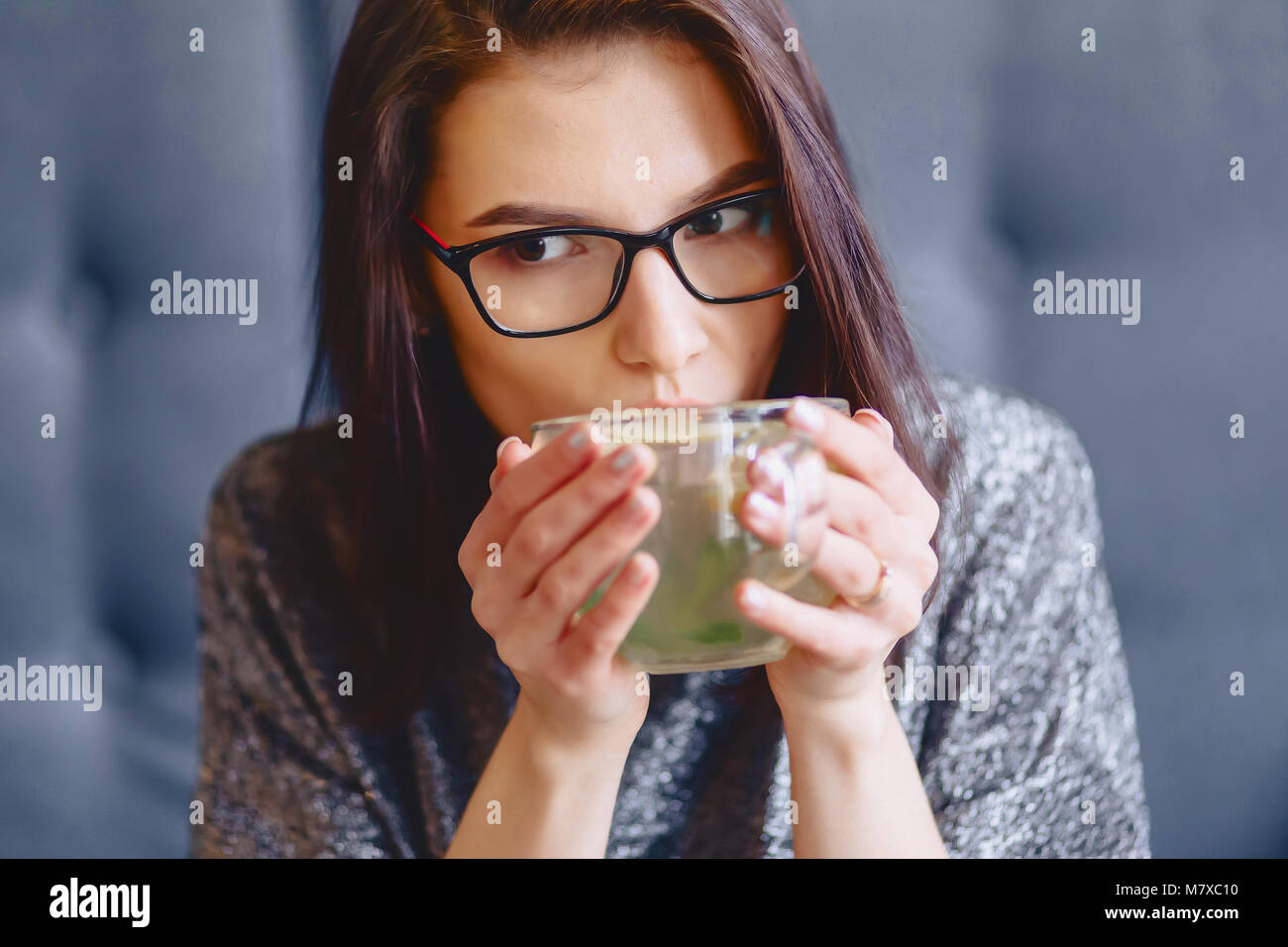 portrait of a young pretty girl drinking hot tea with lemon in a cafe ...