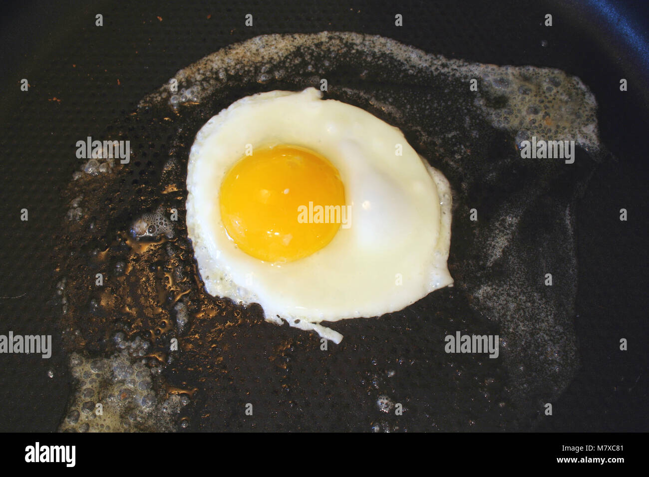 A Sunnyside up egg frying in a pan Stock Photo - Alamy
