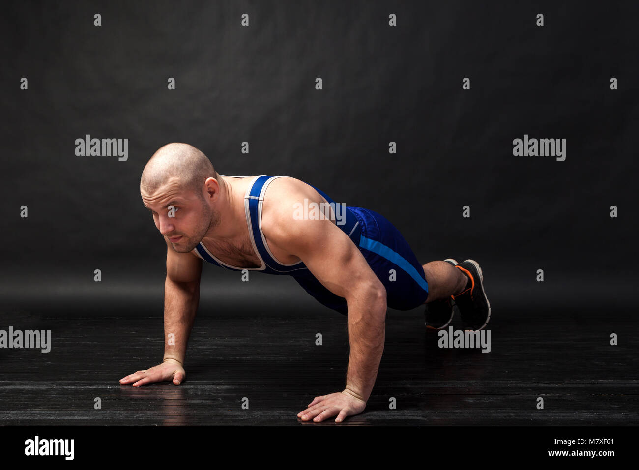 A young athletic man in blue wrestling tricky and blue shorts does push ...