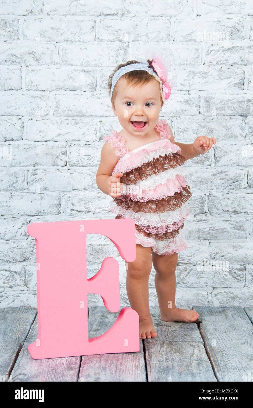 Beautiful and cute girl in pink dress with the letter E. Emotional girl ...