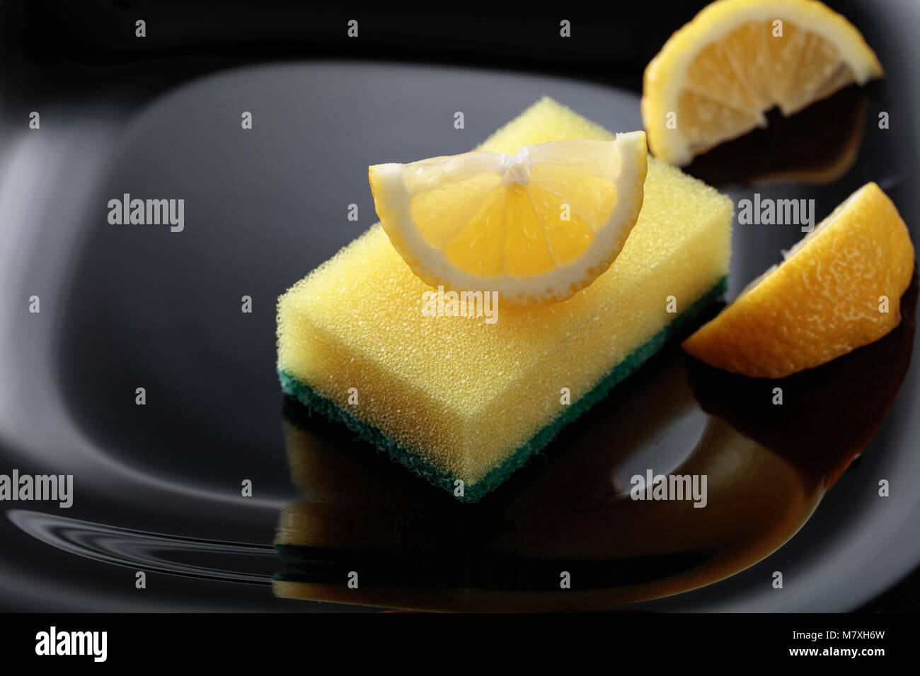 Black plate and dish sponge . Lemon slices . Conceptual image on the ...