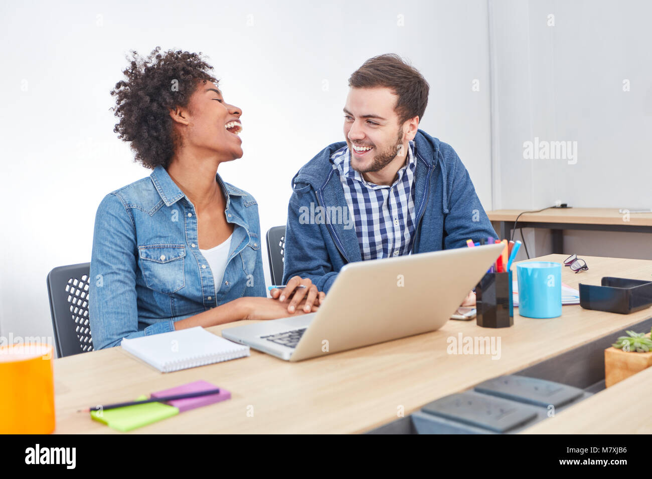 Two students have fun together at the laptop computer in the business ...