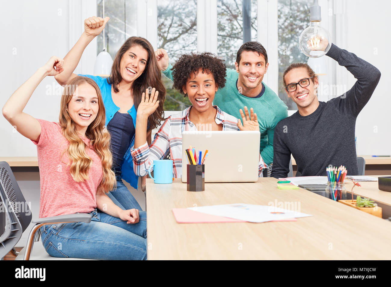 Group of cheering students using laptop as a young successful start-up ...