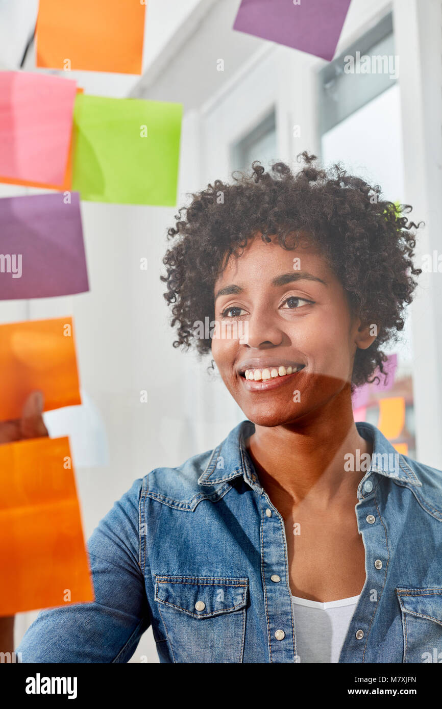 Young start-up woman analyzes ideas on notes in creative business ...