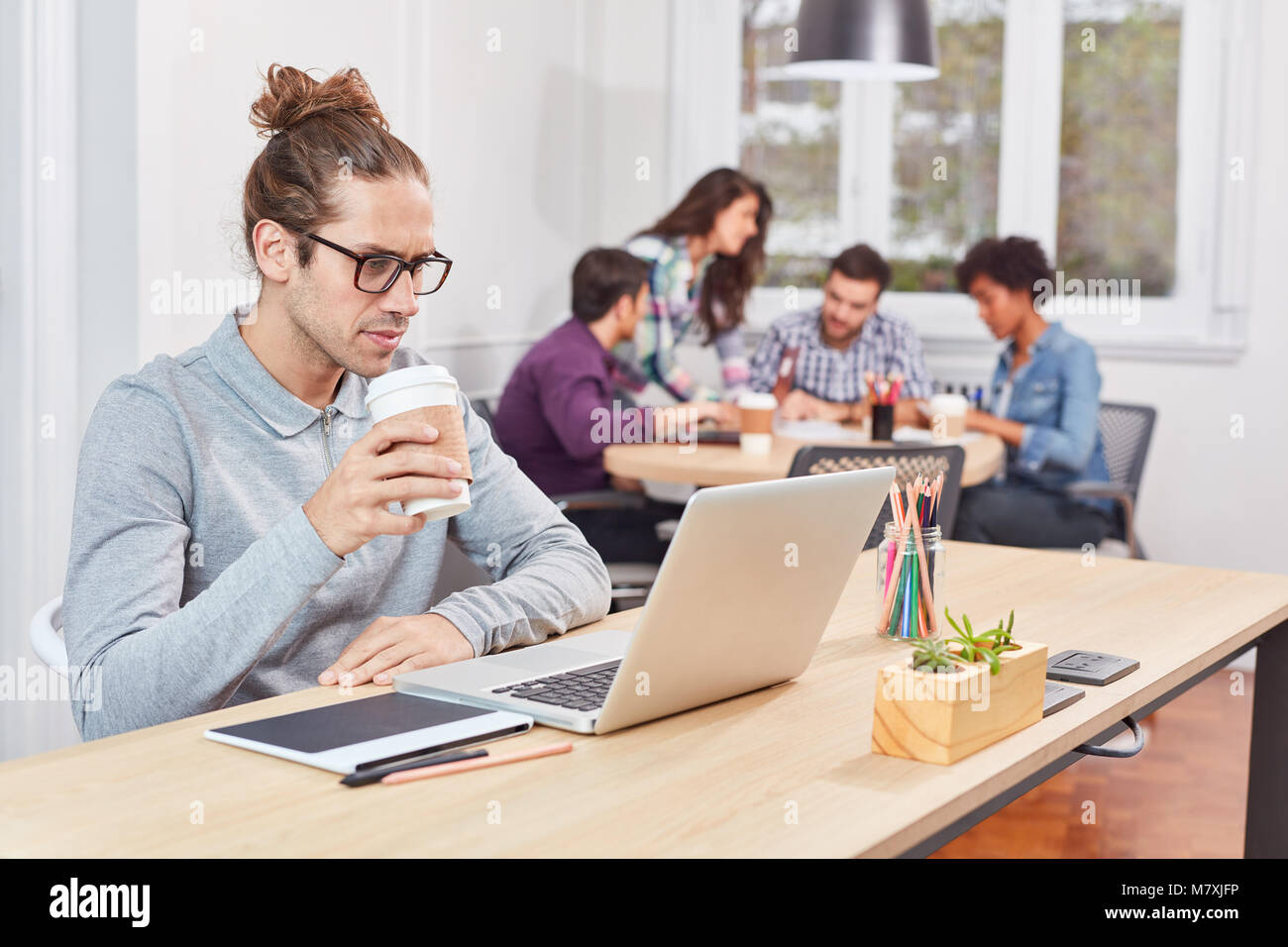 Young computer nerd is working on laptop computer in coworking office ...