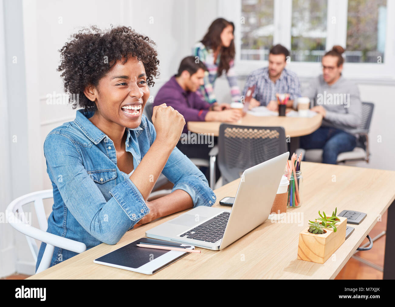 Young business woman in start-up office cheers with clenched fist on ...
