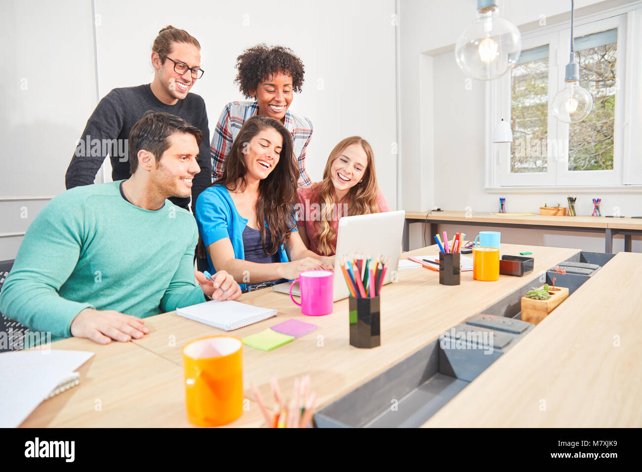 Students on the internet start-up team work together on laptop computer ...