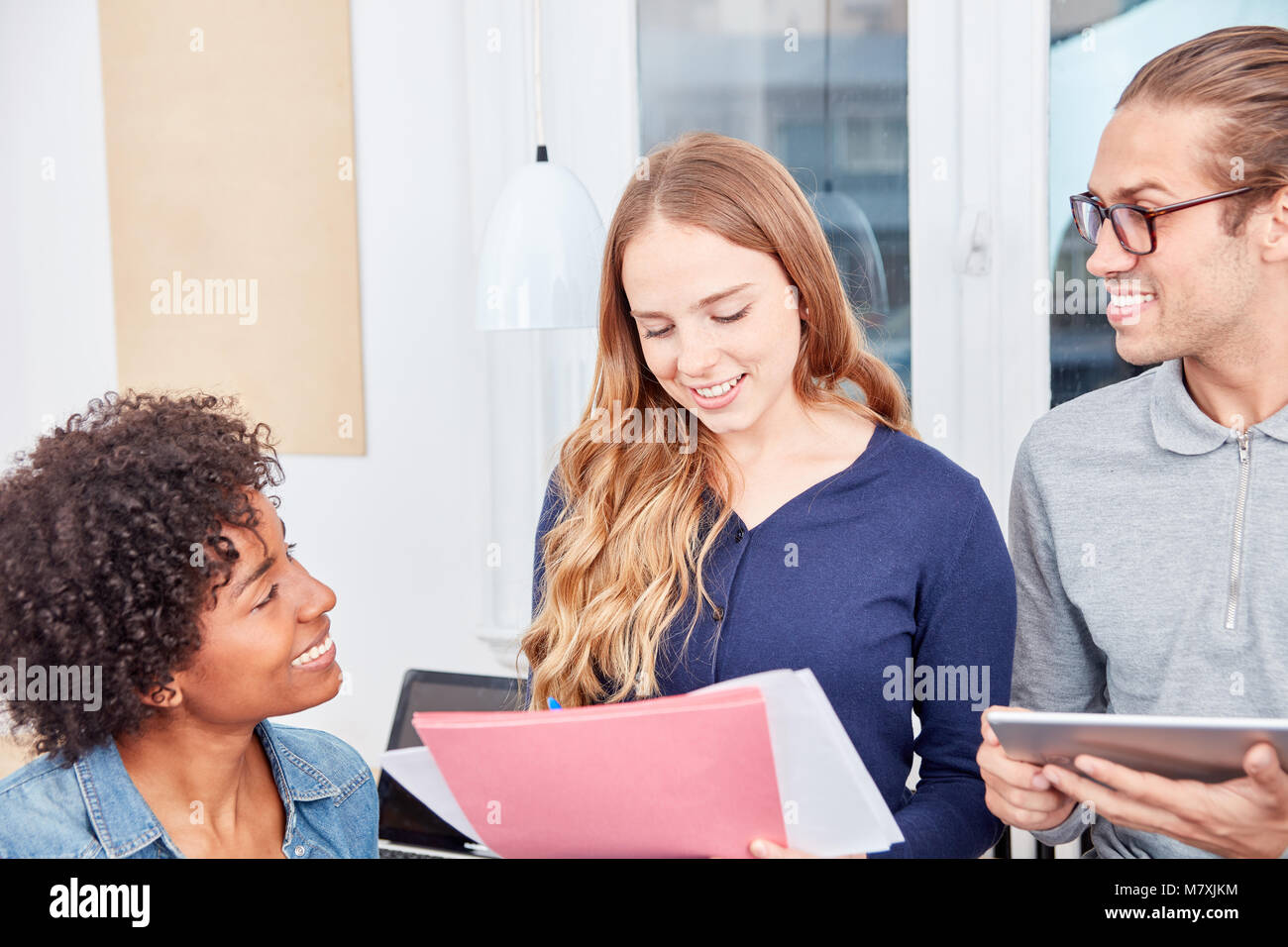 Three young students study together as a team for an exam during their ...