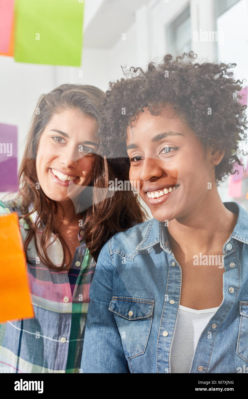 Two young business women in multicultural team in ideas workshop Stock ...