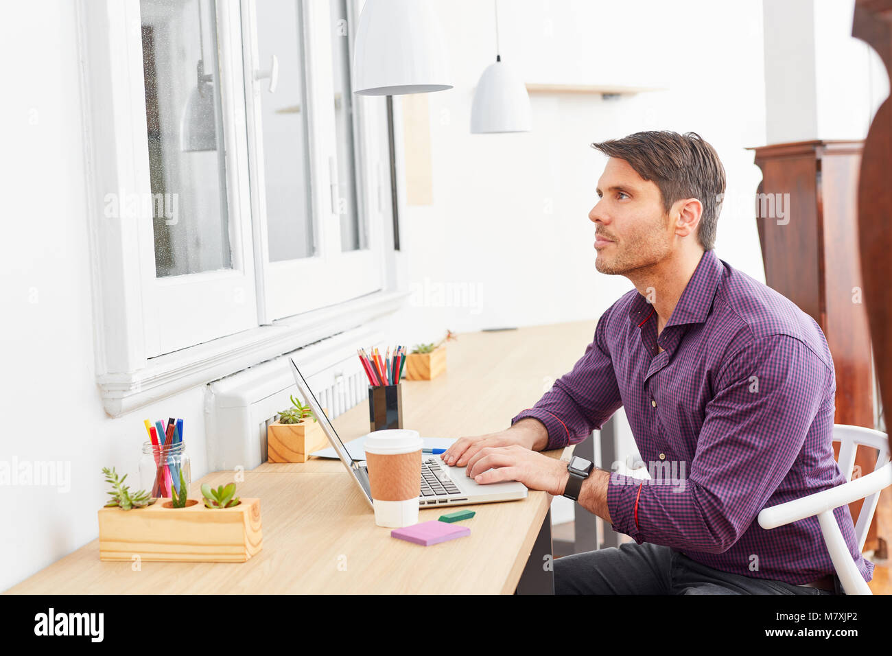 Young man as a founder or programmer is thinking about laptop computer ...