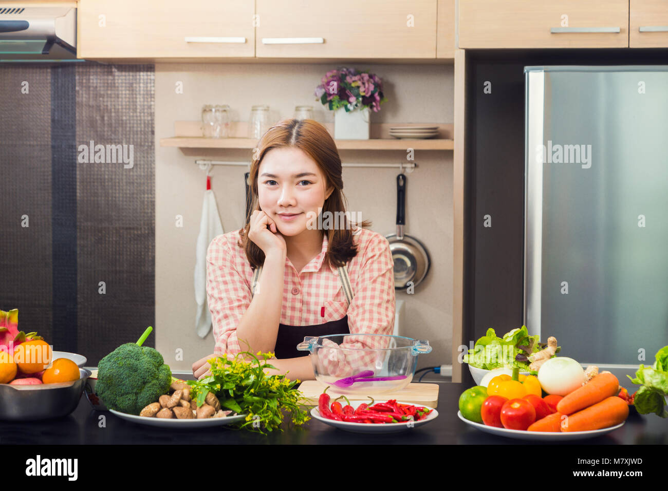 Proud attractive asian female cook standing in her home kitchen and ...