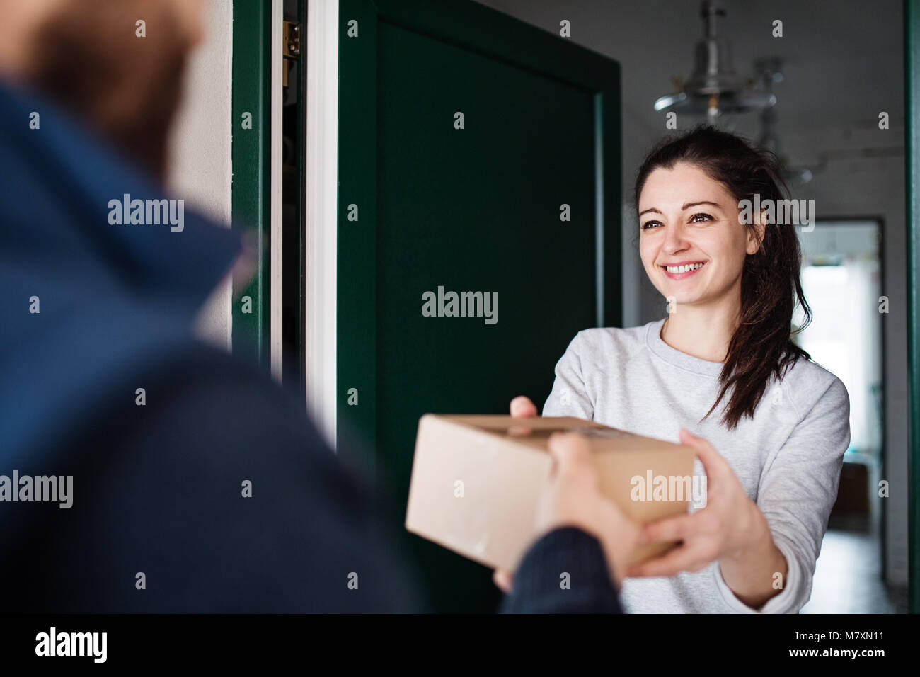 Woman receiving parcel from unrecognizable delivery man at the door ...