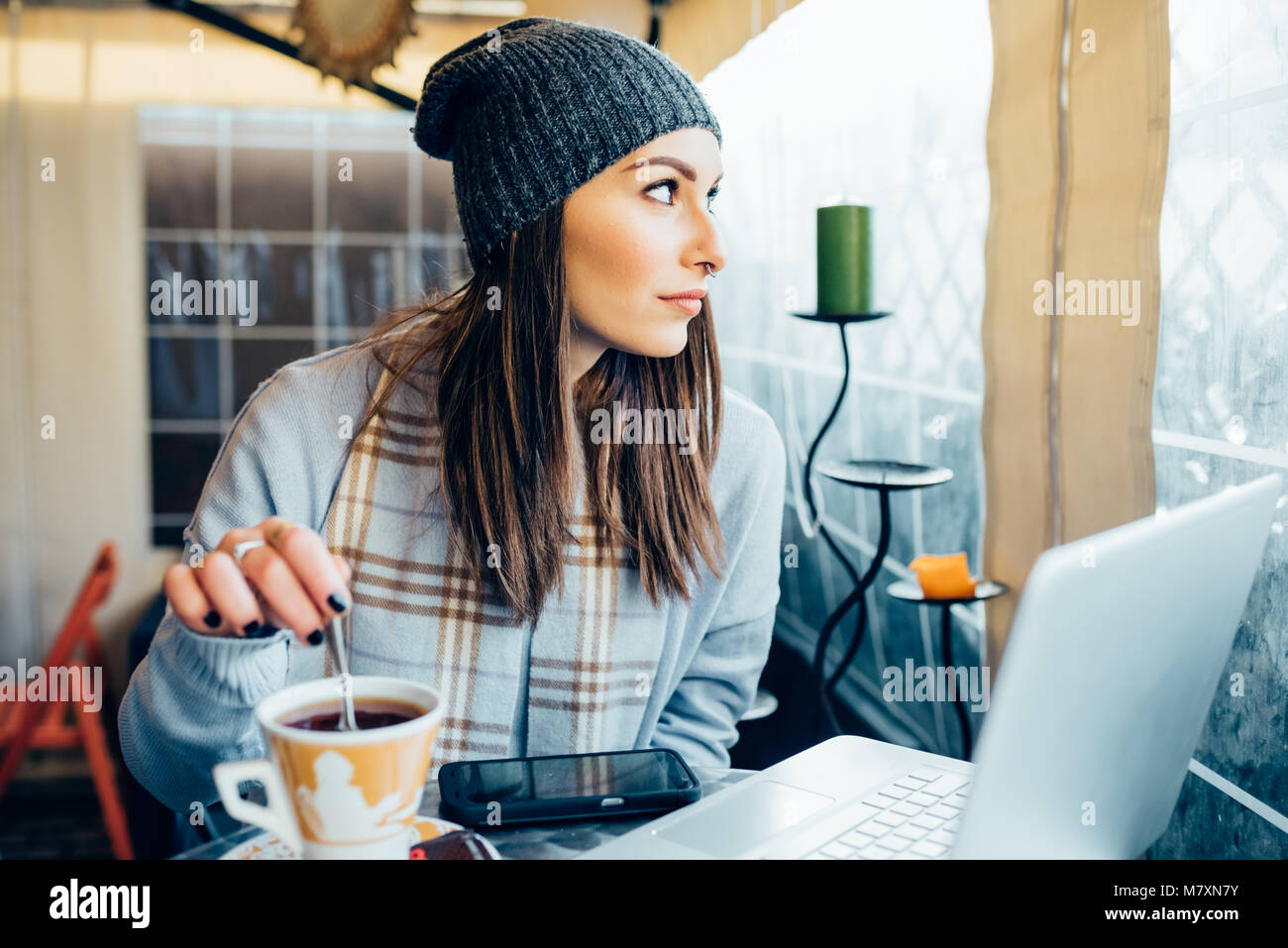 young woman outdoor sitting bat holding teacup looking away pensive ...