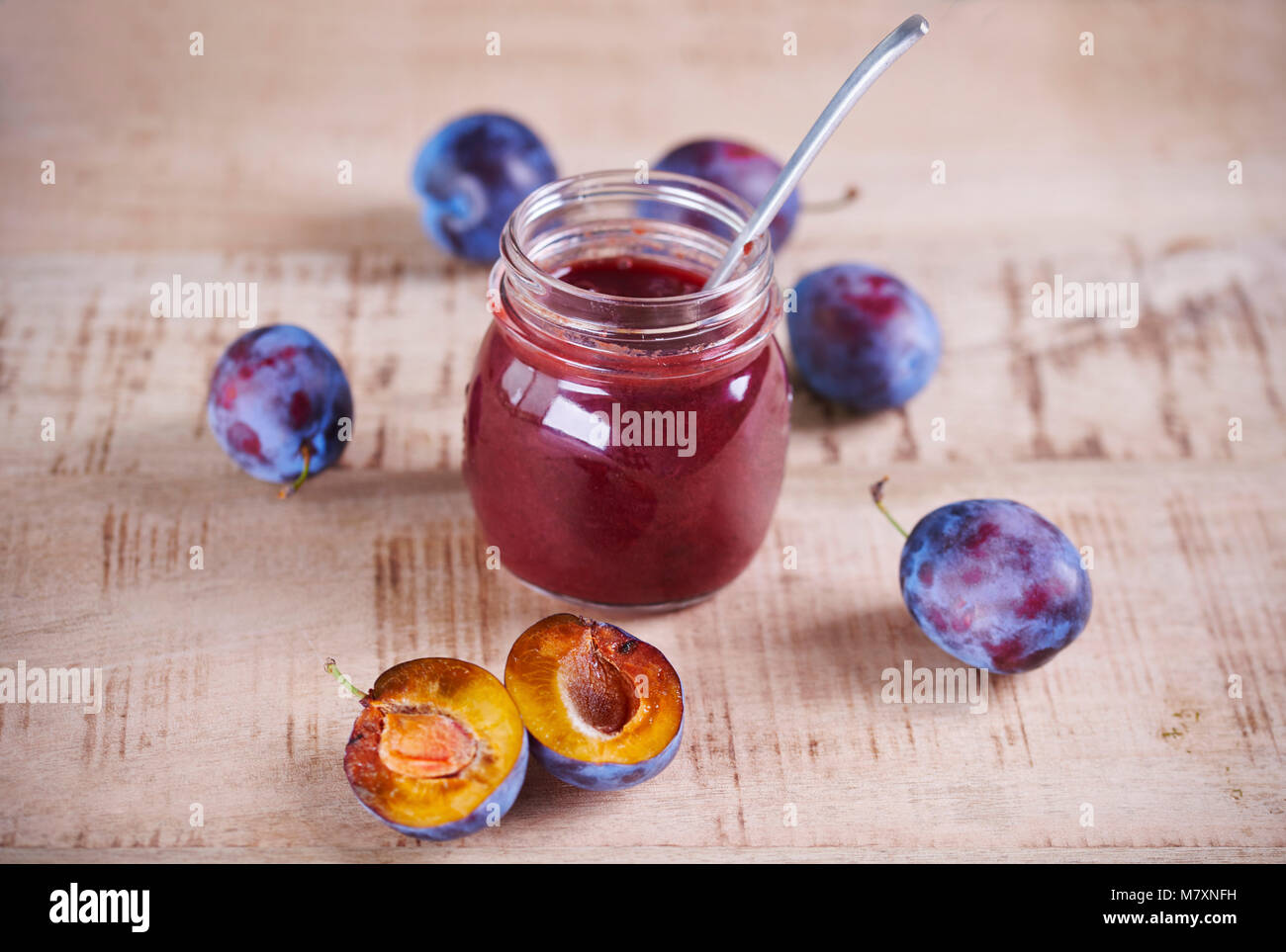 Jar of plum jam with spoon on wooden table Stock Photo - Alamy