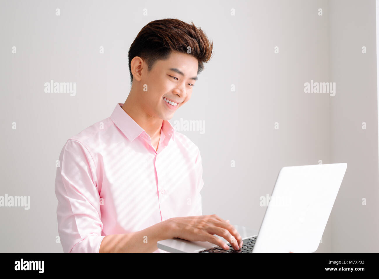 Handsome asian man standing with laptop in office Stock Photo - Alamy