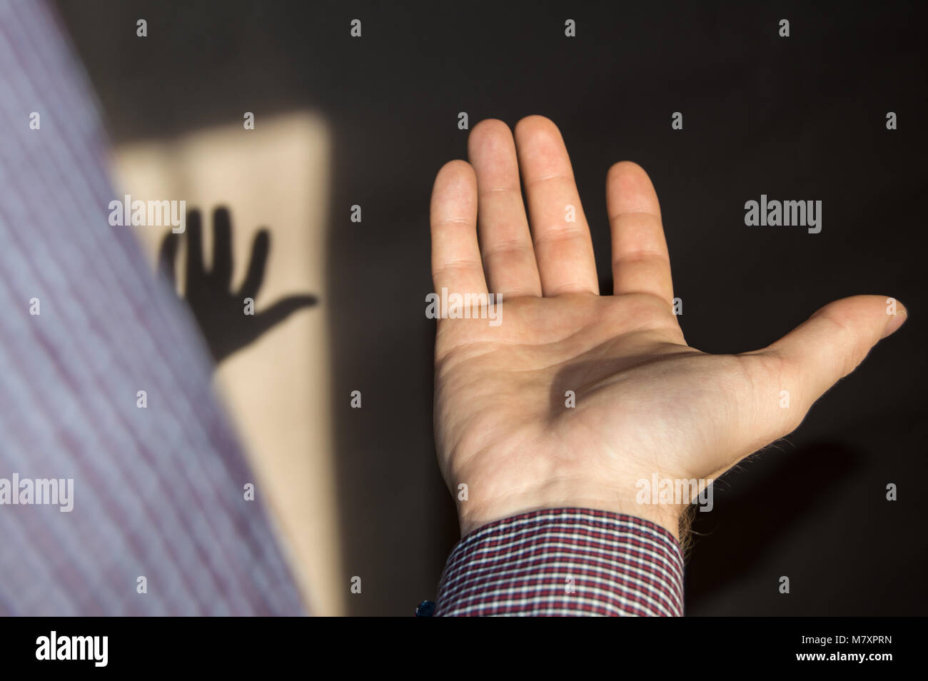 The young man holds an empty hand with his palm up, a shadow on the ...