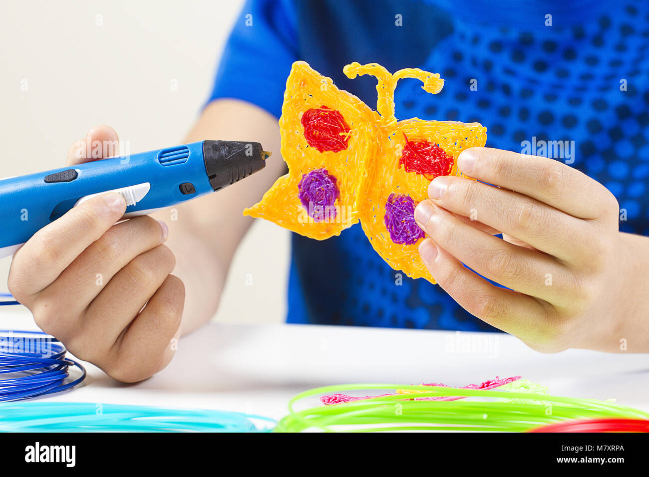 Kid hands creating with blue 3d pen Stock Photo - Alamy